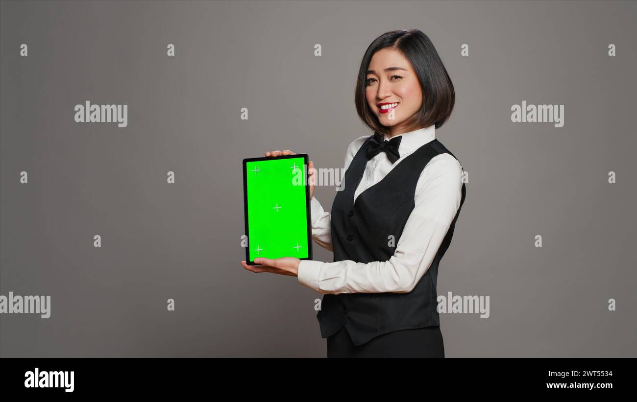Woman concierge presenting greenscreen display on tablet, showing ...