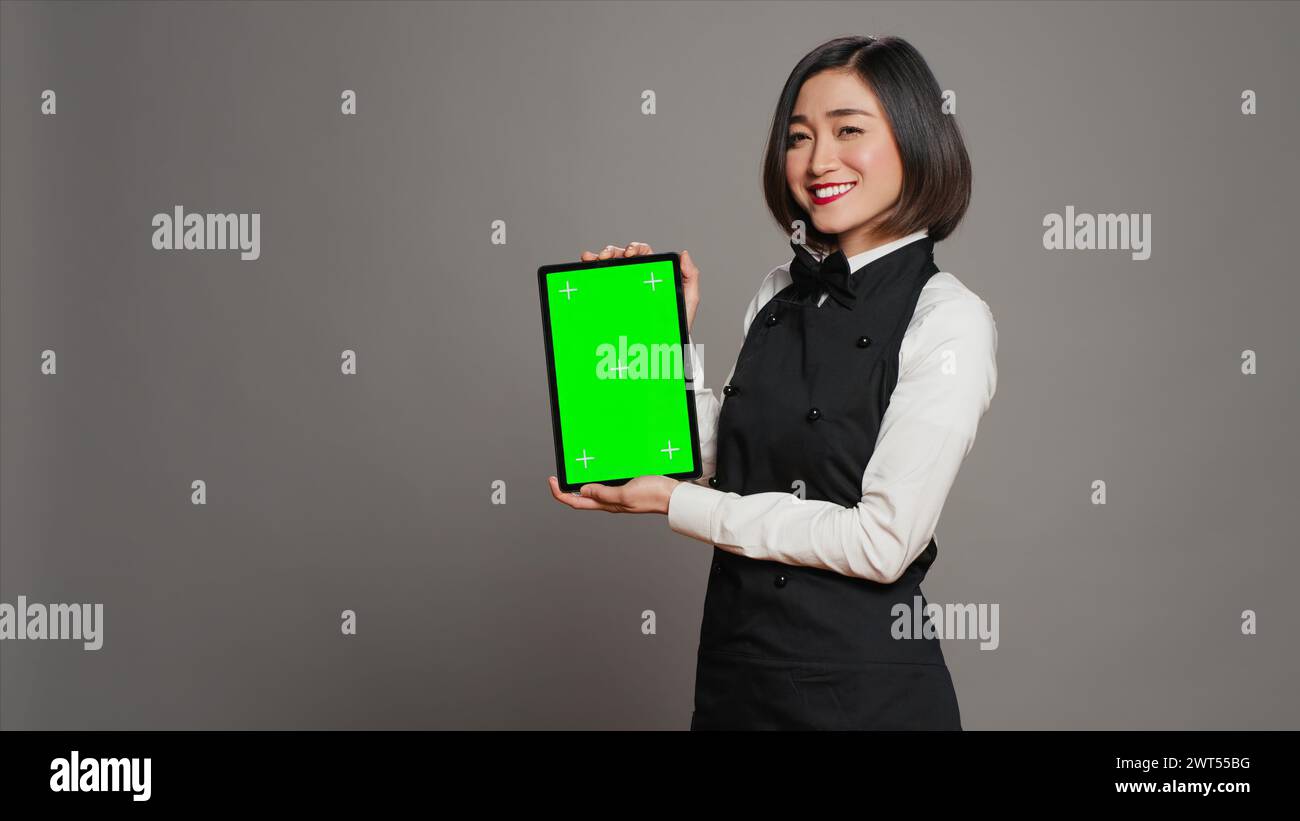Asian restaurant hostess showing greenscreen display in studio ...