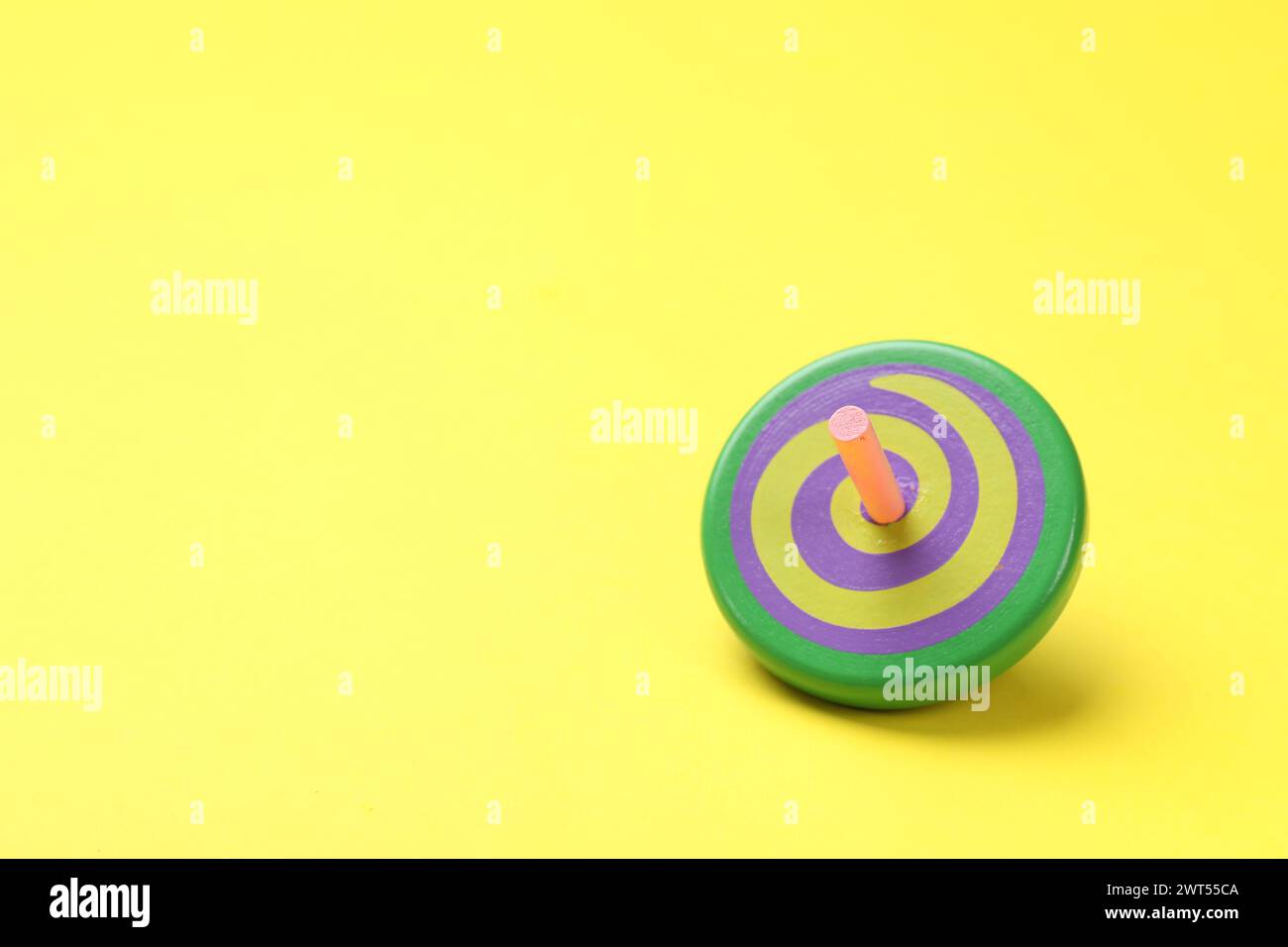One colorful spinning top on yellow background, space for text Stock ...