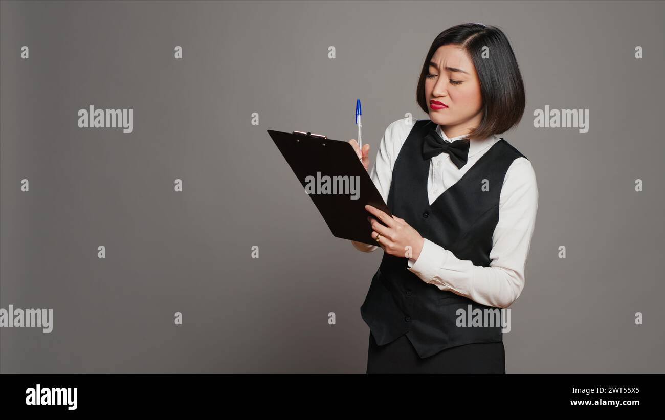 Hotel administrator checking off names of room reservations list ...