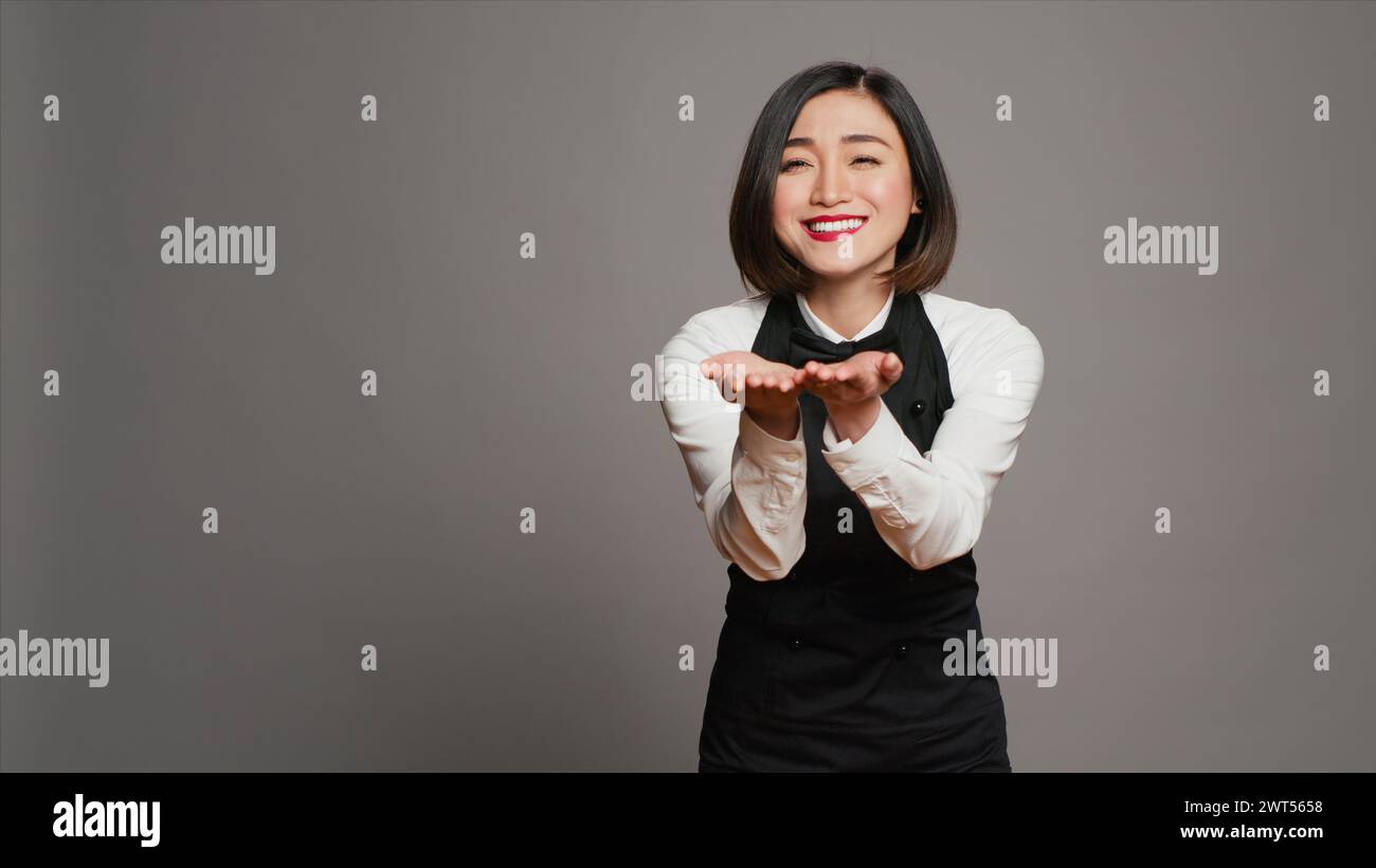 Cute flirty waitress blowing air kisses in front of camera, acting ...