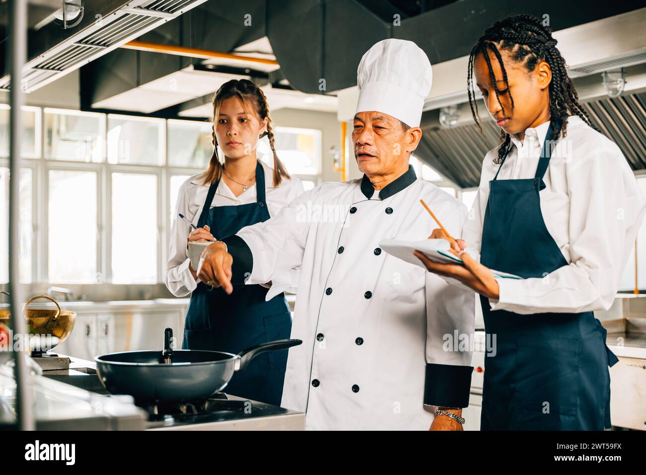 Professional Asian senior chef teaches diverse students cooking in a ...