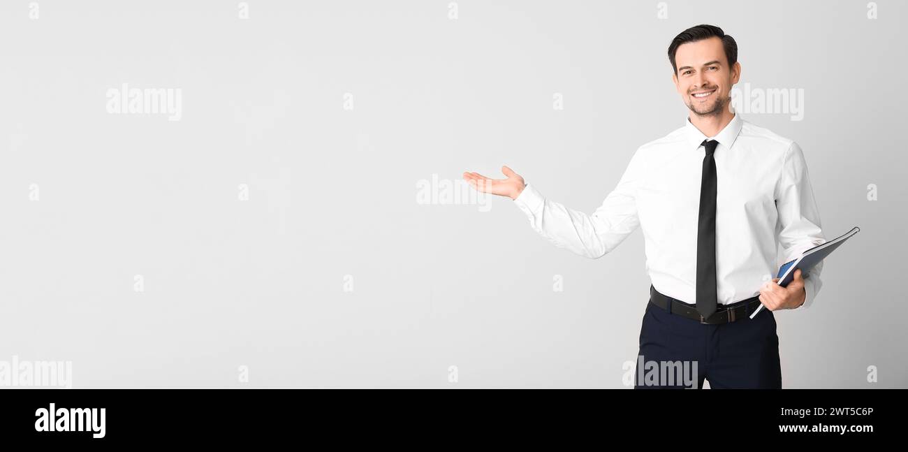 Male real estate agent showing something on grey background with space ...