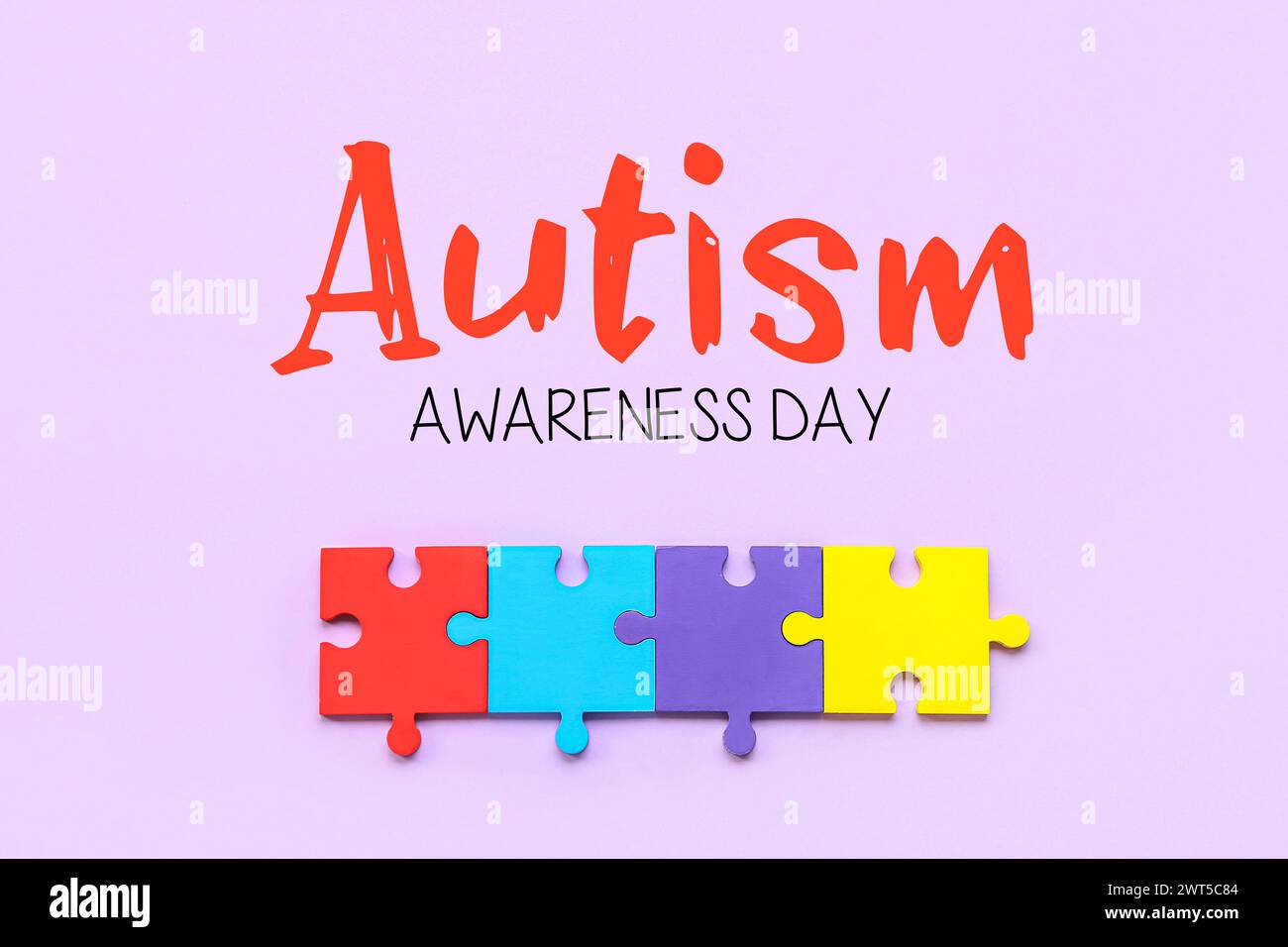 Colorful jigsaw puzzle pieces and text AUTISM AWARENESS DAY on lilac ...