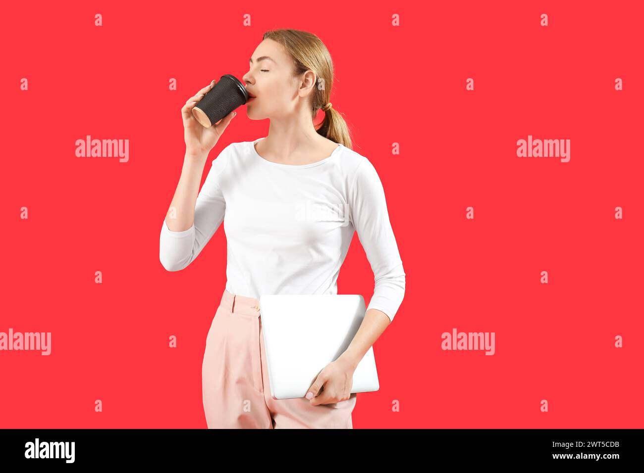 Female programmer with laptop drinking coffee on red background Stock ...