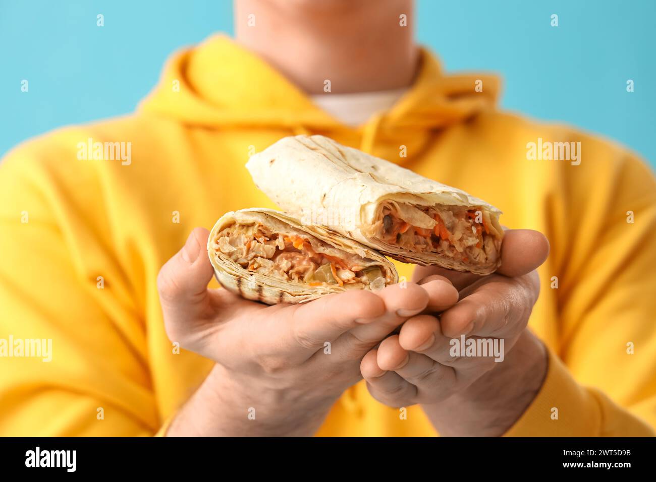 Man holding doner kebab on blue background, closeup Stock Photo - Alamy