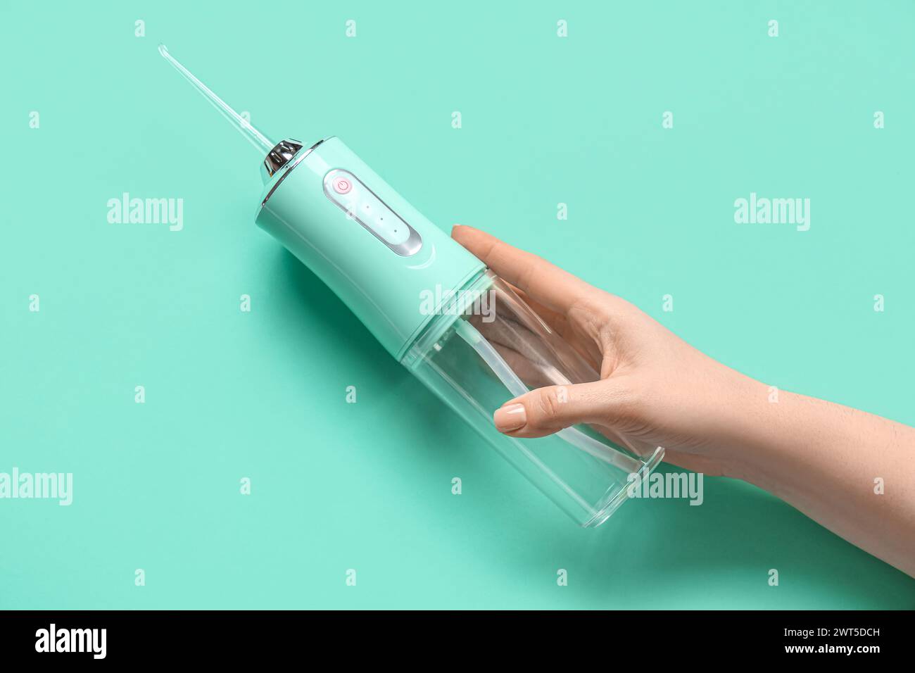 Female hand holding oral irrigator on turquoise background Stock Photo ...