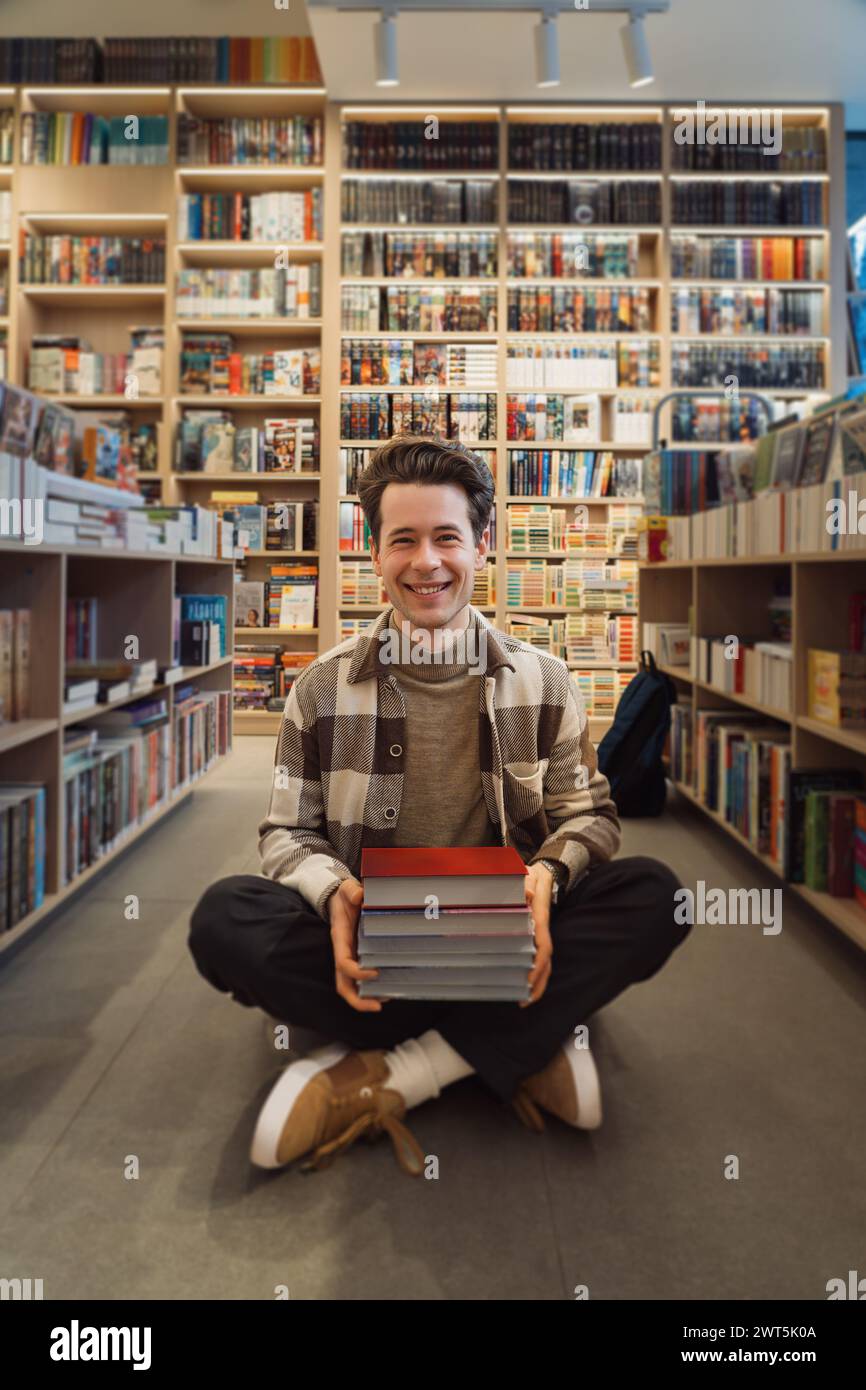 Young man smiling with books in modern library interior Stock Photo - Alamy