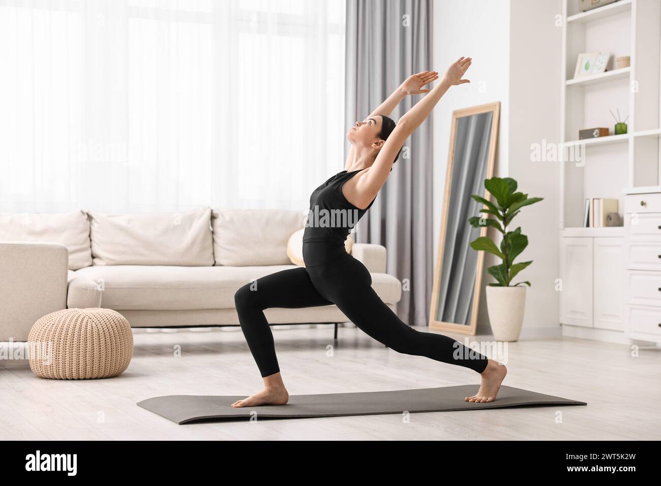 Girl practicing crescent asana on yoga mat at home. High lunge pose ...