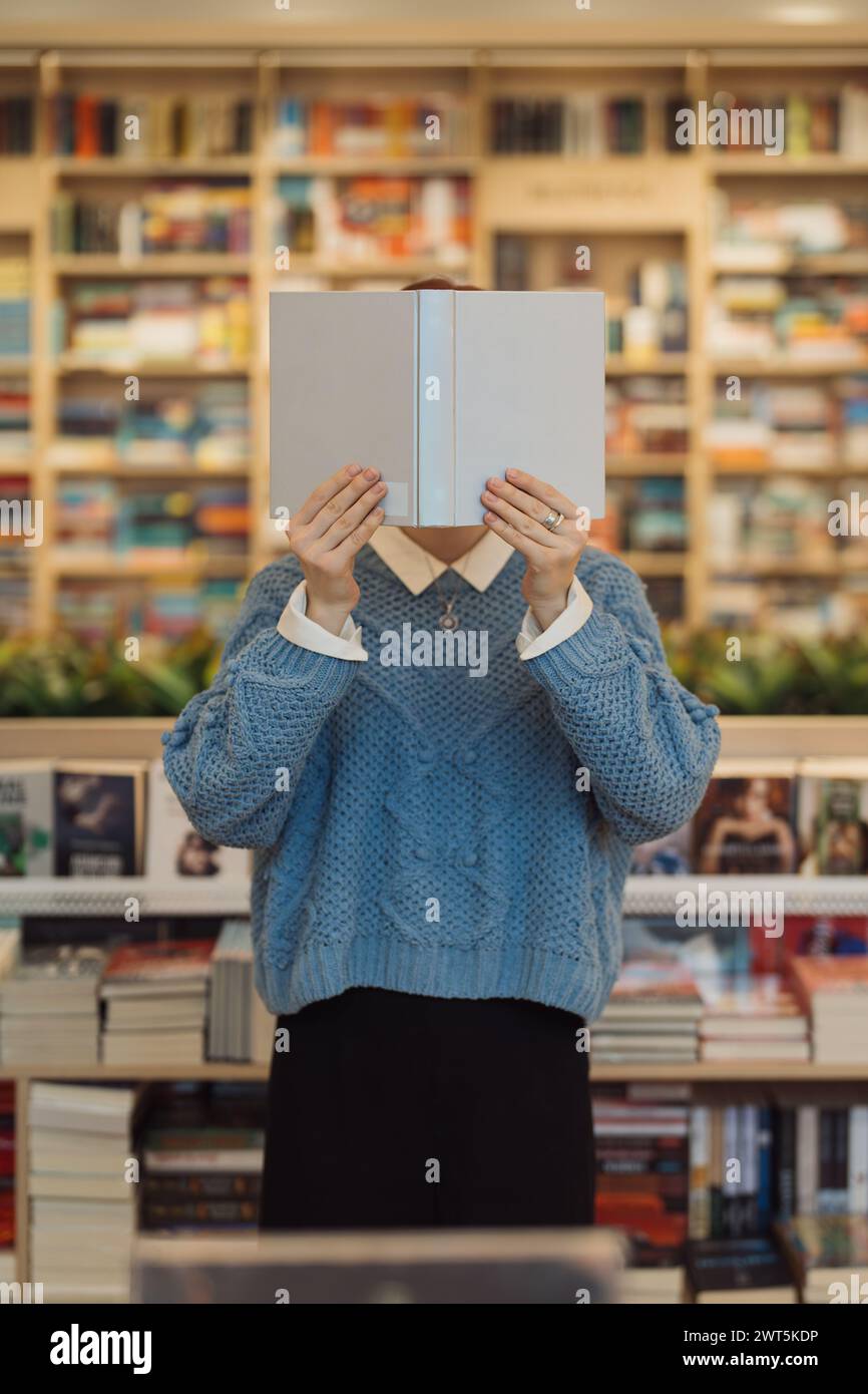 Person reading a book hiding face in library Stock Photo - Alamy