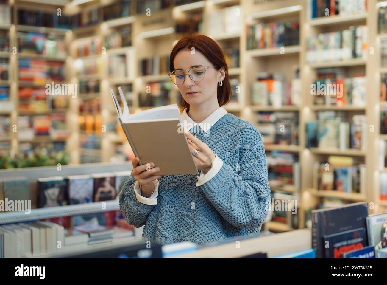 Concentrated young woman reading in a cozy library Stock Photo - Alamy