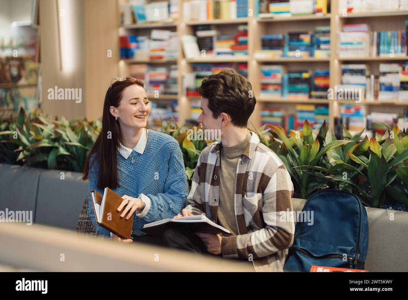 Two friends sharing a laugh in a cozy library setting Stock Photo - Alamy