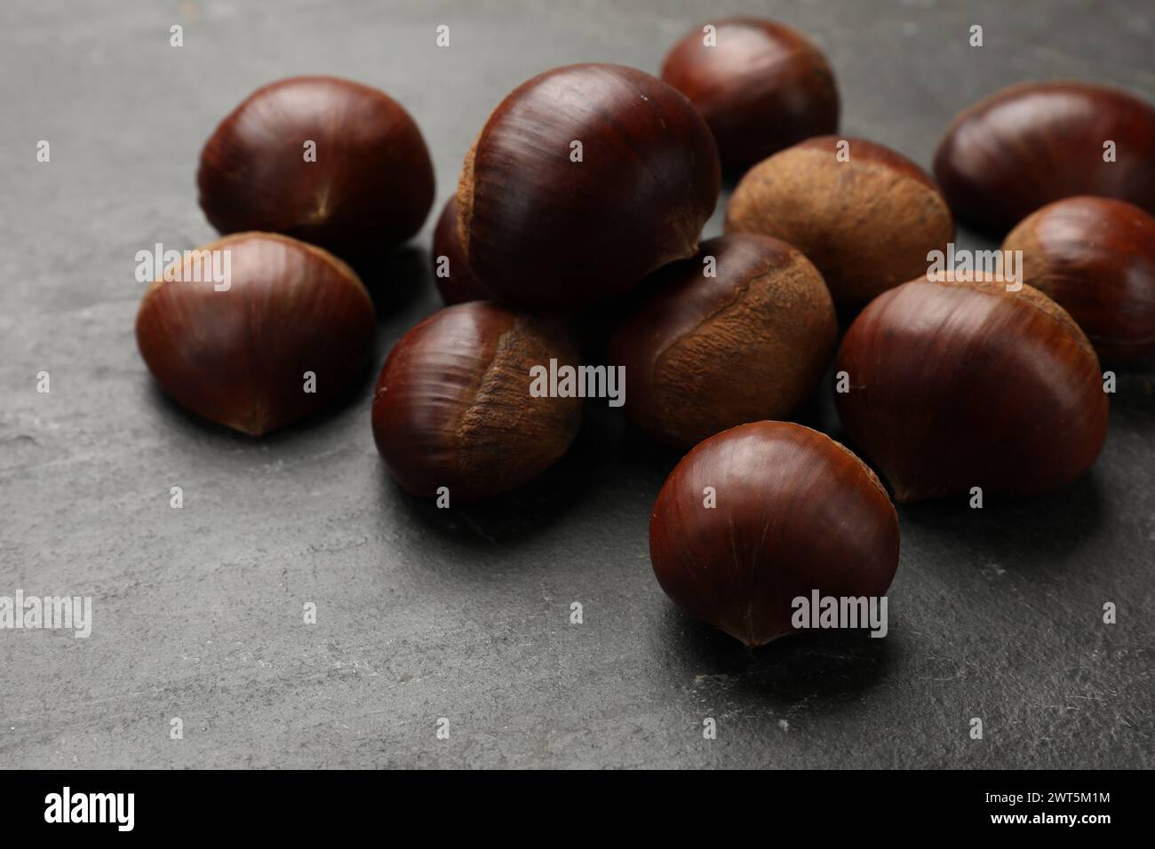 Roasted edible sweet chestnuts on grey textured table, closeup Stock ...