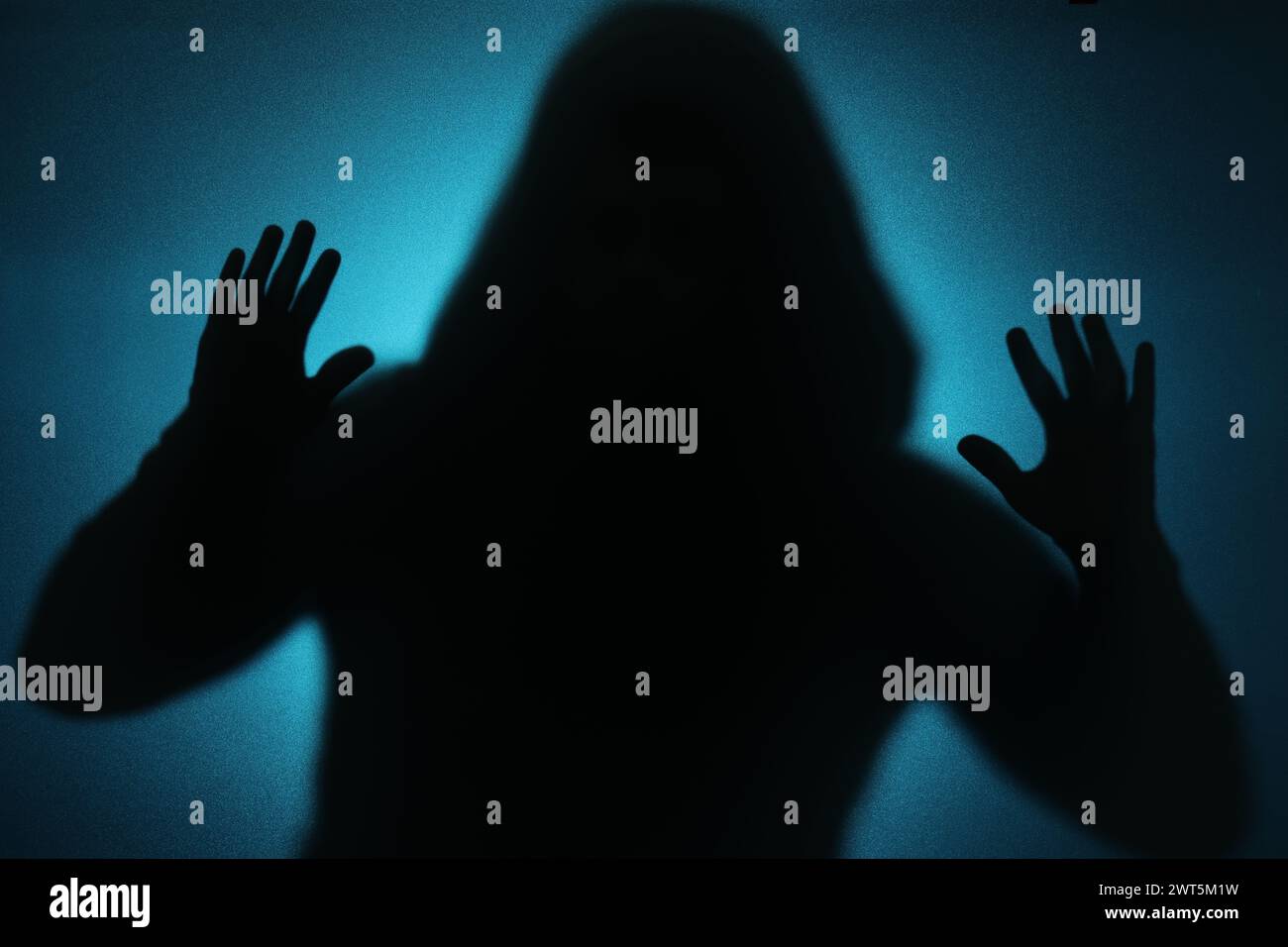 Silhouette of ghost behind glass against blue background Stock Photo ...