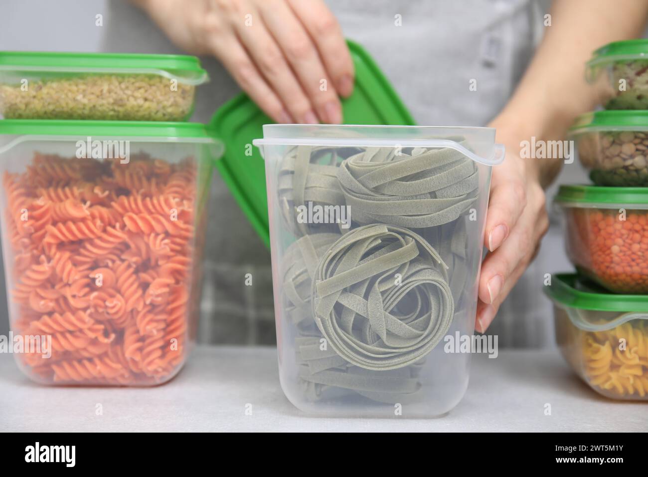 Woman with plastic containers filled of food products at light table ...