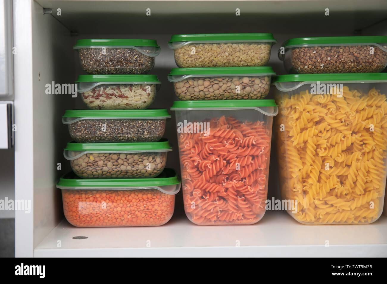 Plastic containers filled with food products in kitchen cabinet ...