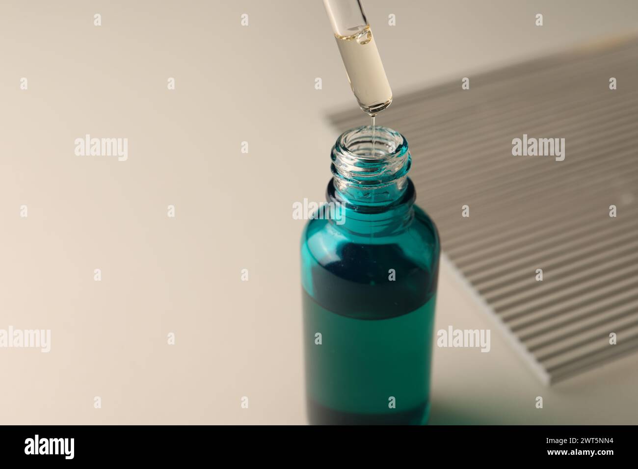 Dripping moisturizing serum from pipette into bottle on light ...