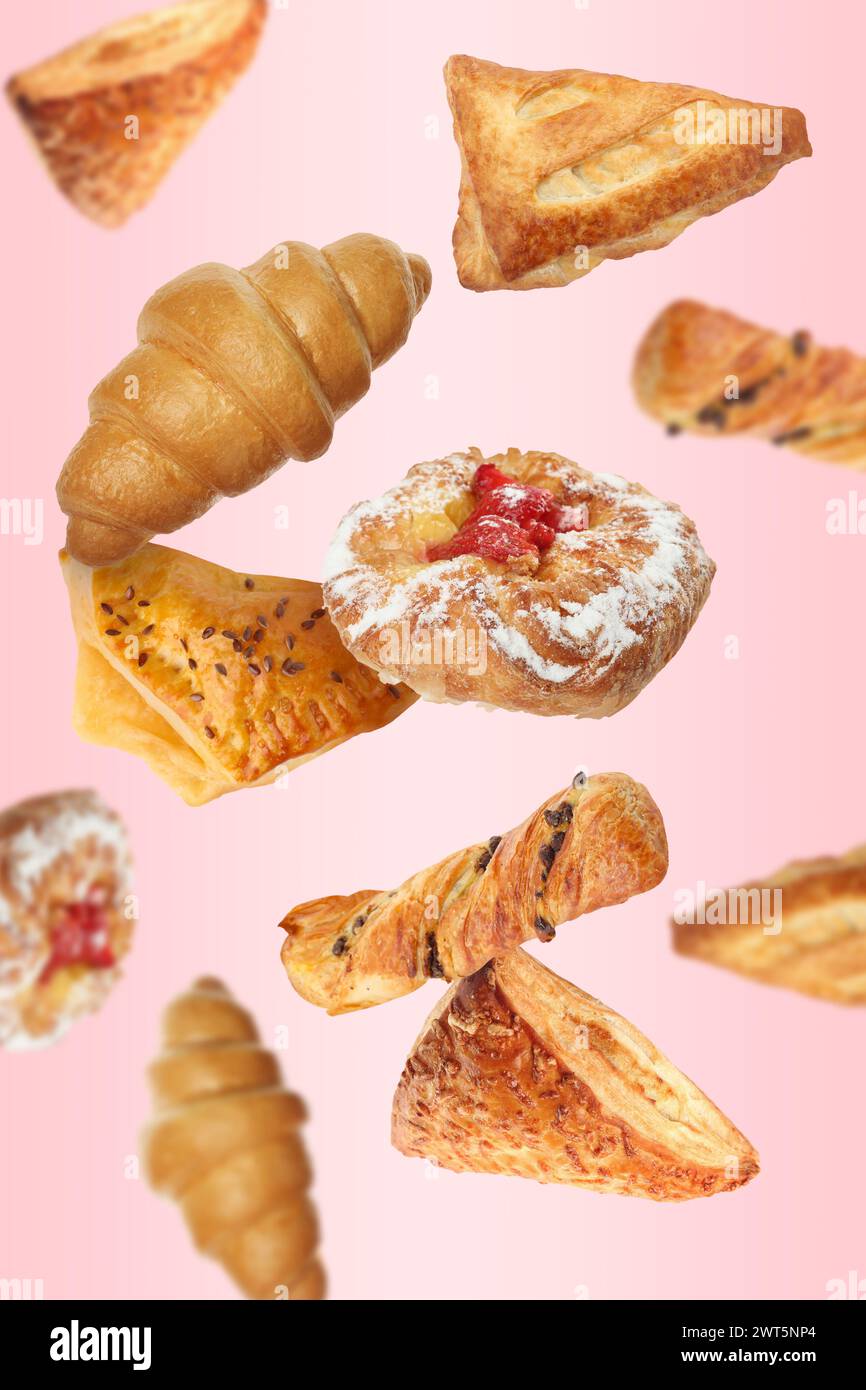 Different tasty puff pastries falling on pink background Stock Photo ...