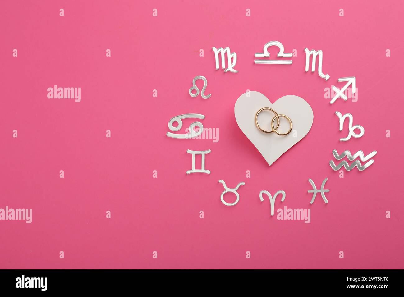 Zodiac signs, heart and wedding rings on pink background, flat lay ...