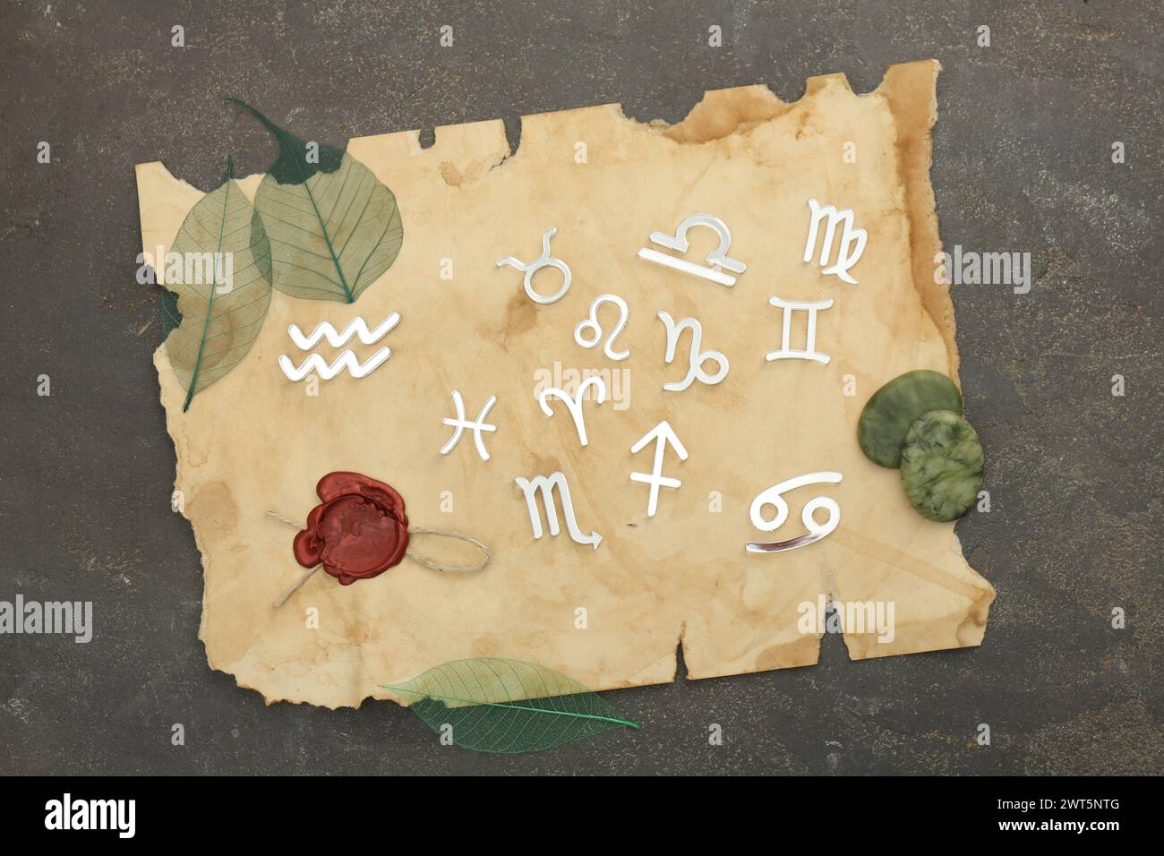 Zodiac signs, stones and old paper on grey textured table, flat lay ...