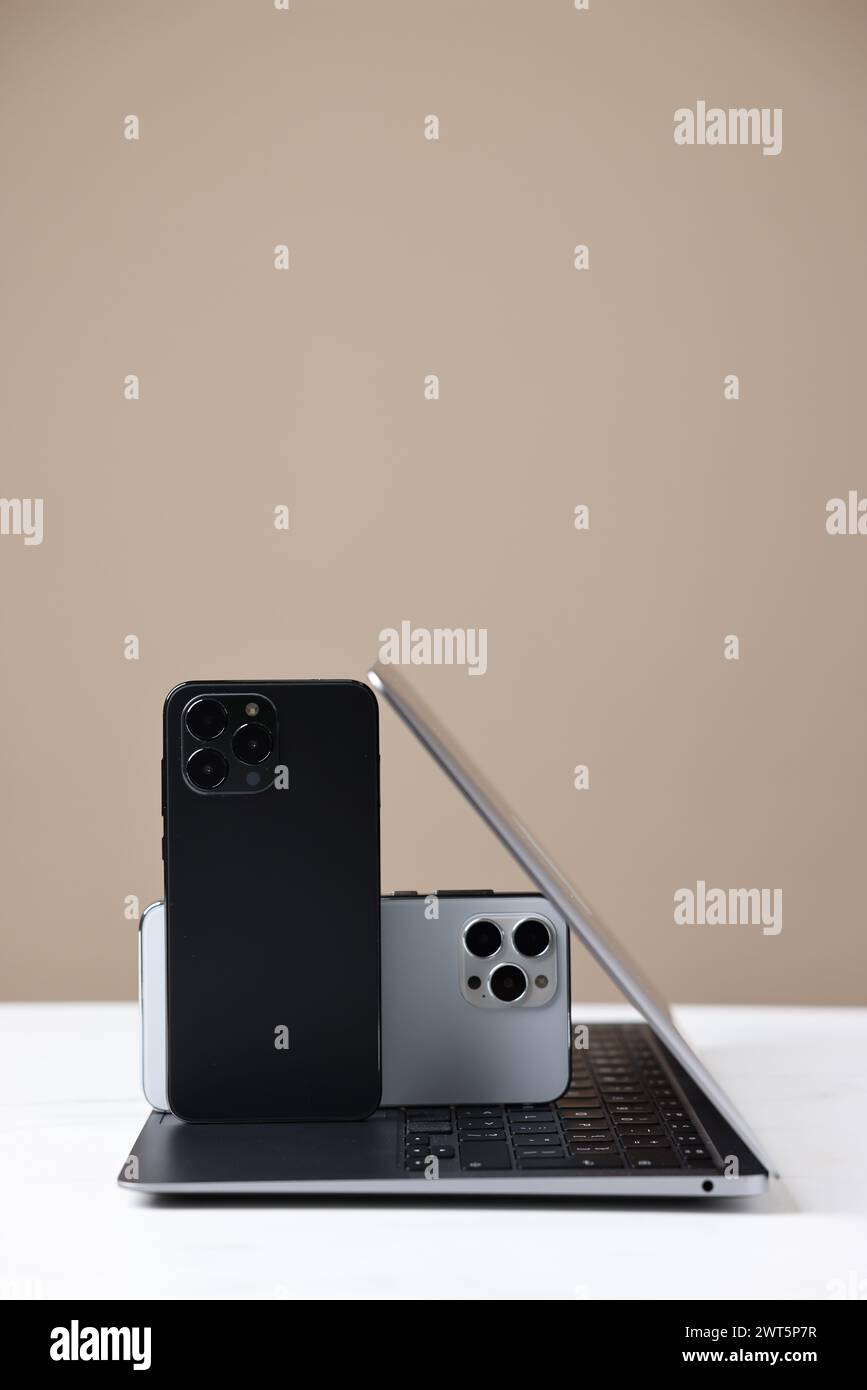 Modern laptop and smartphones on beige background Stock Photo - Alamy