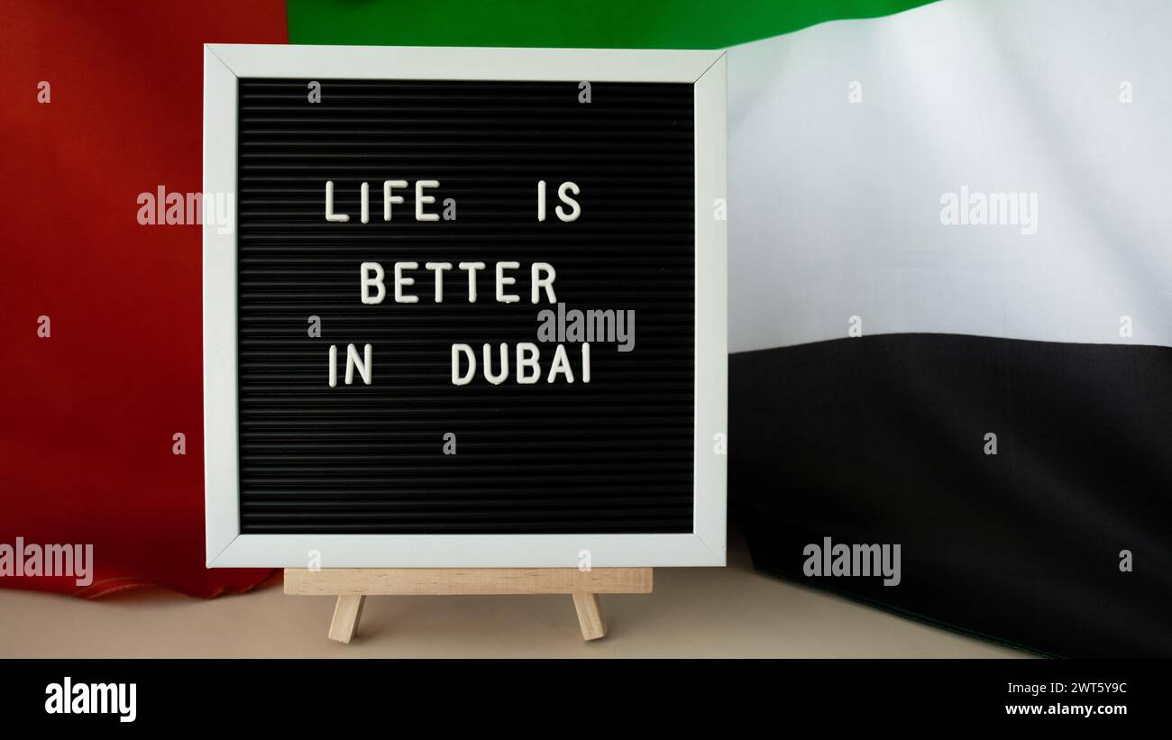 Message LIFE IS BETTER IN DUBAI on background of waving UAE flag made ...