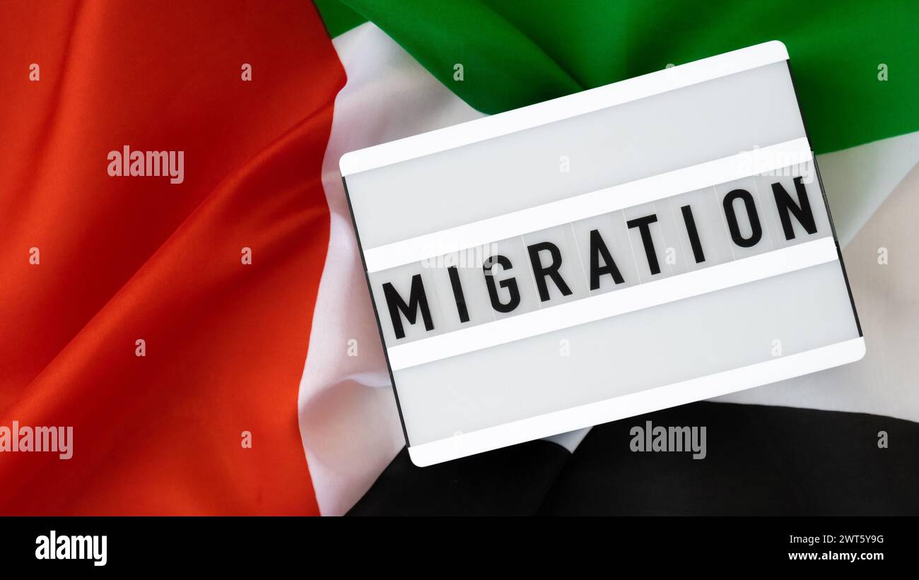 Message MIGRATION on background of UAE flag made from silk. United Arab ...