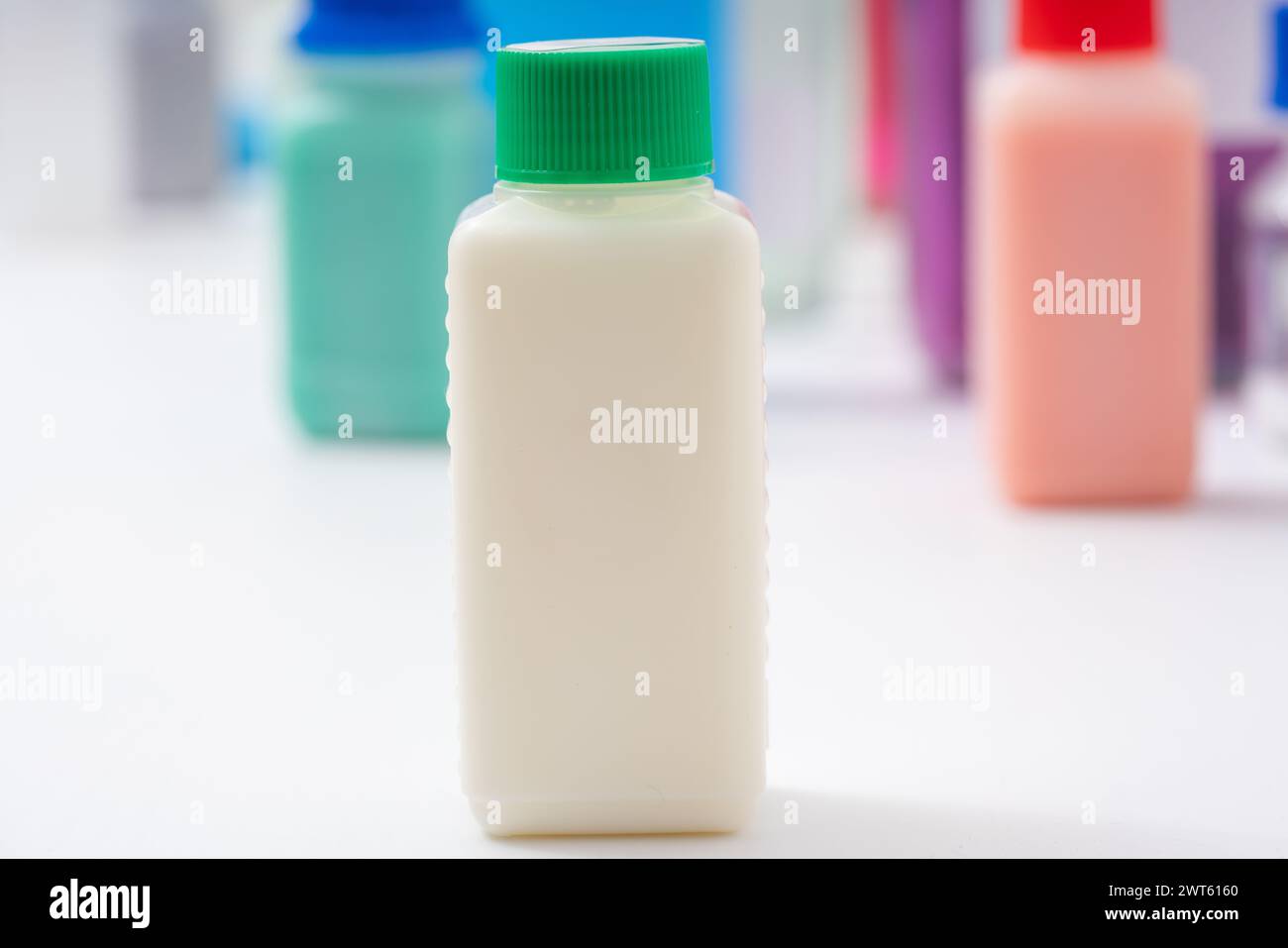 Plastic bottle with white liquid. Samples of food colouring in a food ...