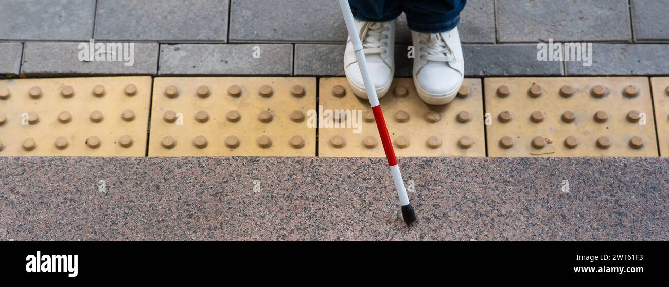 Close-up of female foot, walking stick and tactile tiles. Widescreen ...