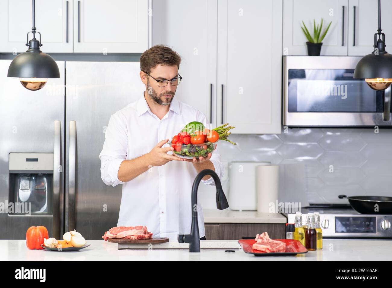 Middle aged man cooking in kitchen. Man on kitchen with vegetables ...