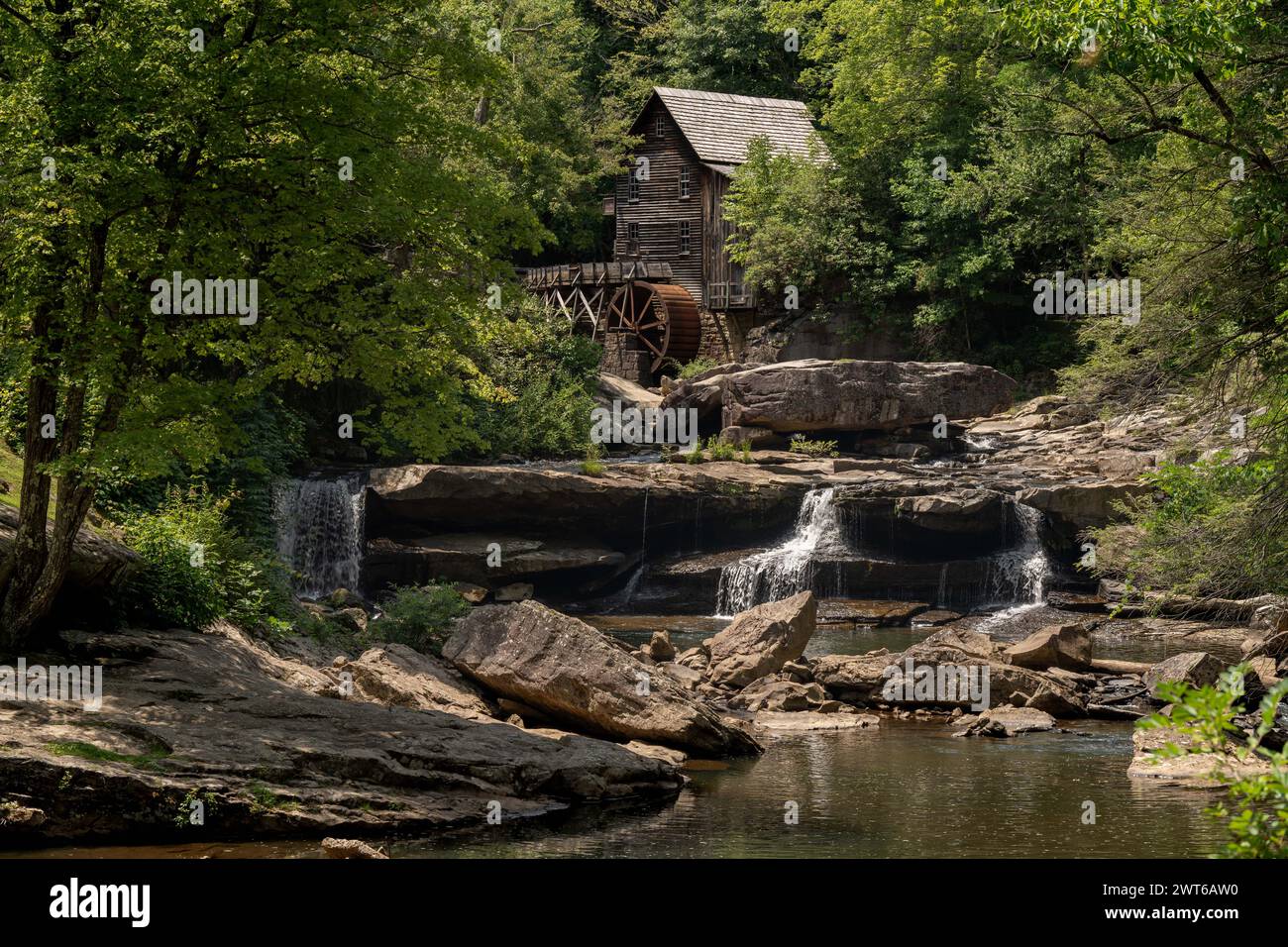 A picturesque water mill surrounded by cascading waterfalls in a serene ...