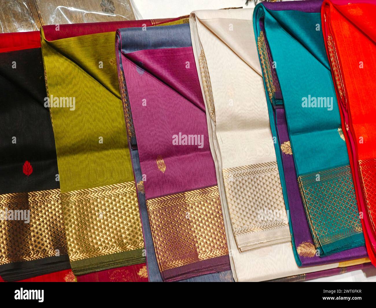 Closeup view of stacked saris or sarees in display of retail shop, for ...