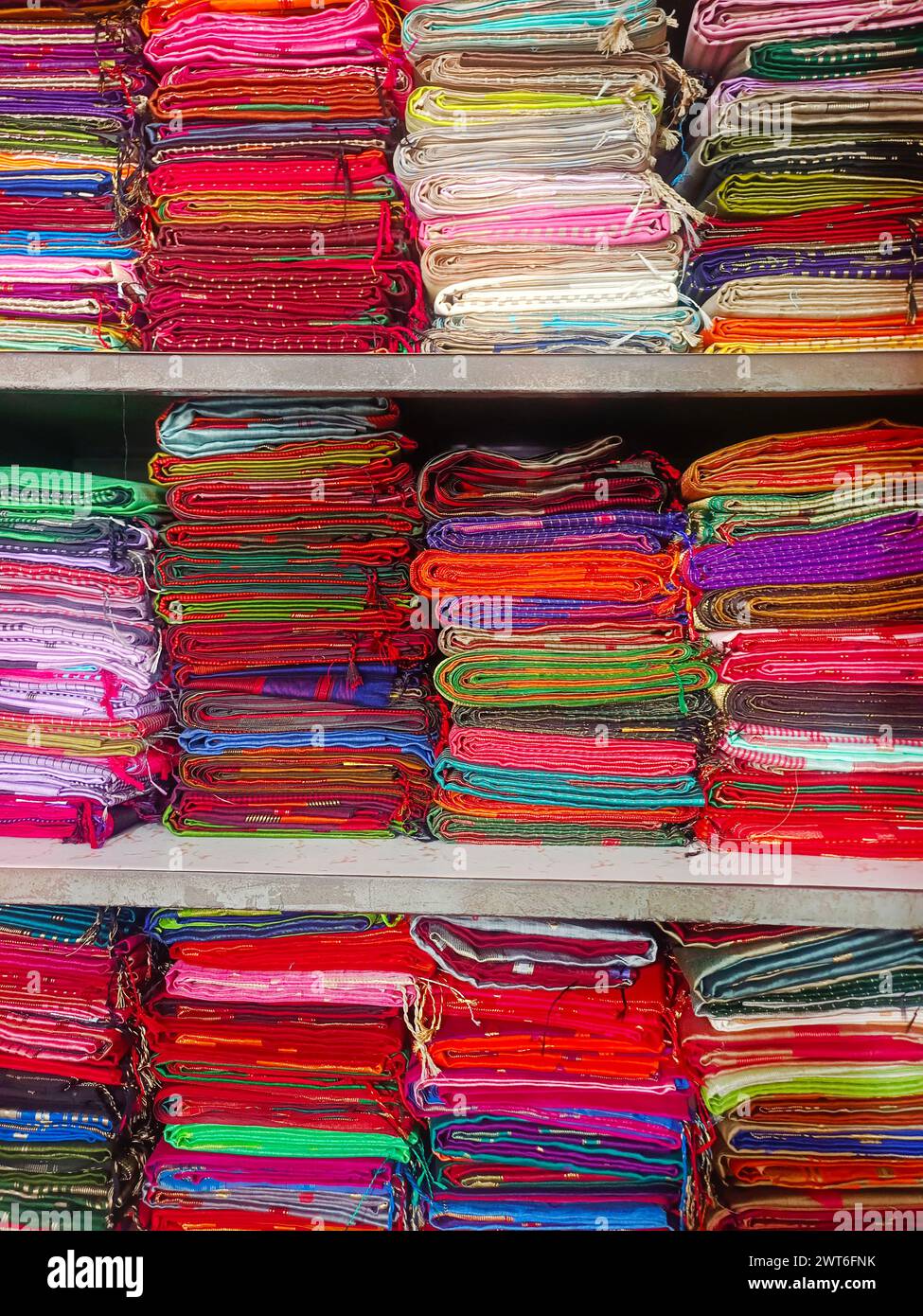 Neatly stacked colorful designer silk saris in racks in a textile shop ...