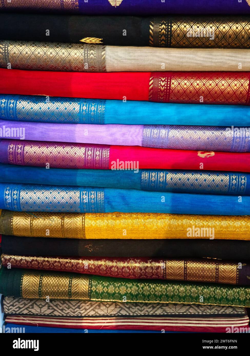 Neatly stacked colorful designer silk saris in racks in a textile shop ...