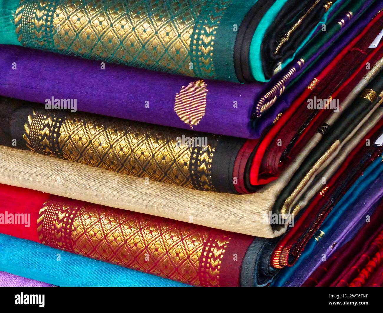 Neatly stacked colorful designer silk saris in racks in a textile shop ...