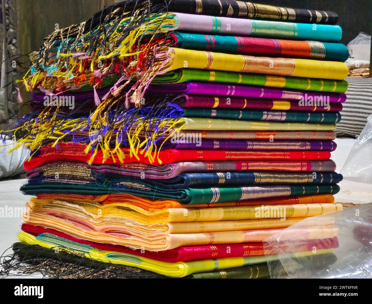 Neatly stacked colorful designer silk saris in racks in a textile shop ...