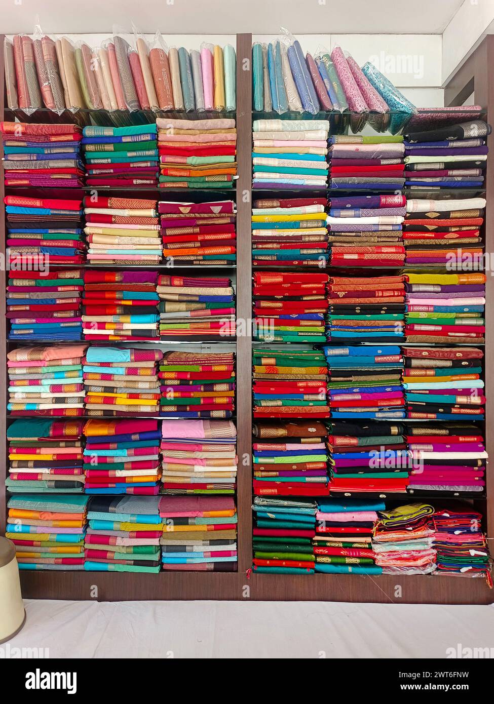 Neatly stacked colorful designer silk saris in racks in a textile shop ...