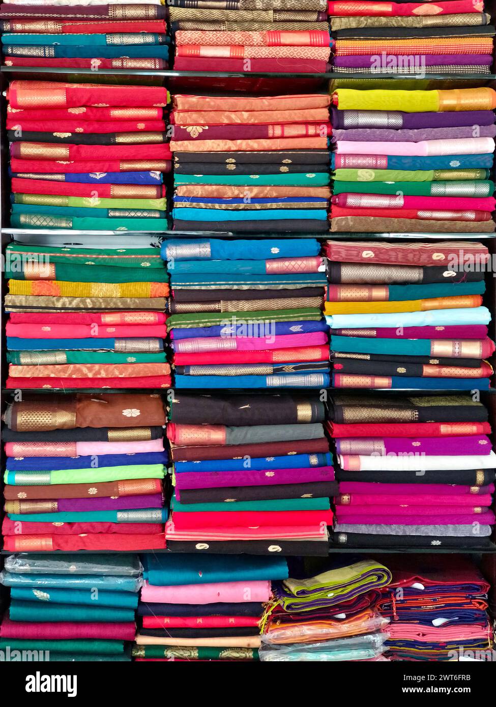 Neatly stacked colorful designer silk saris in racks in a textile shop ...