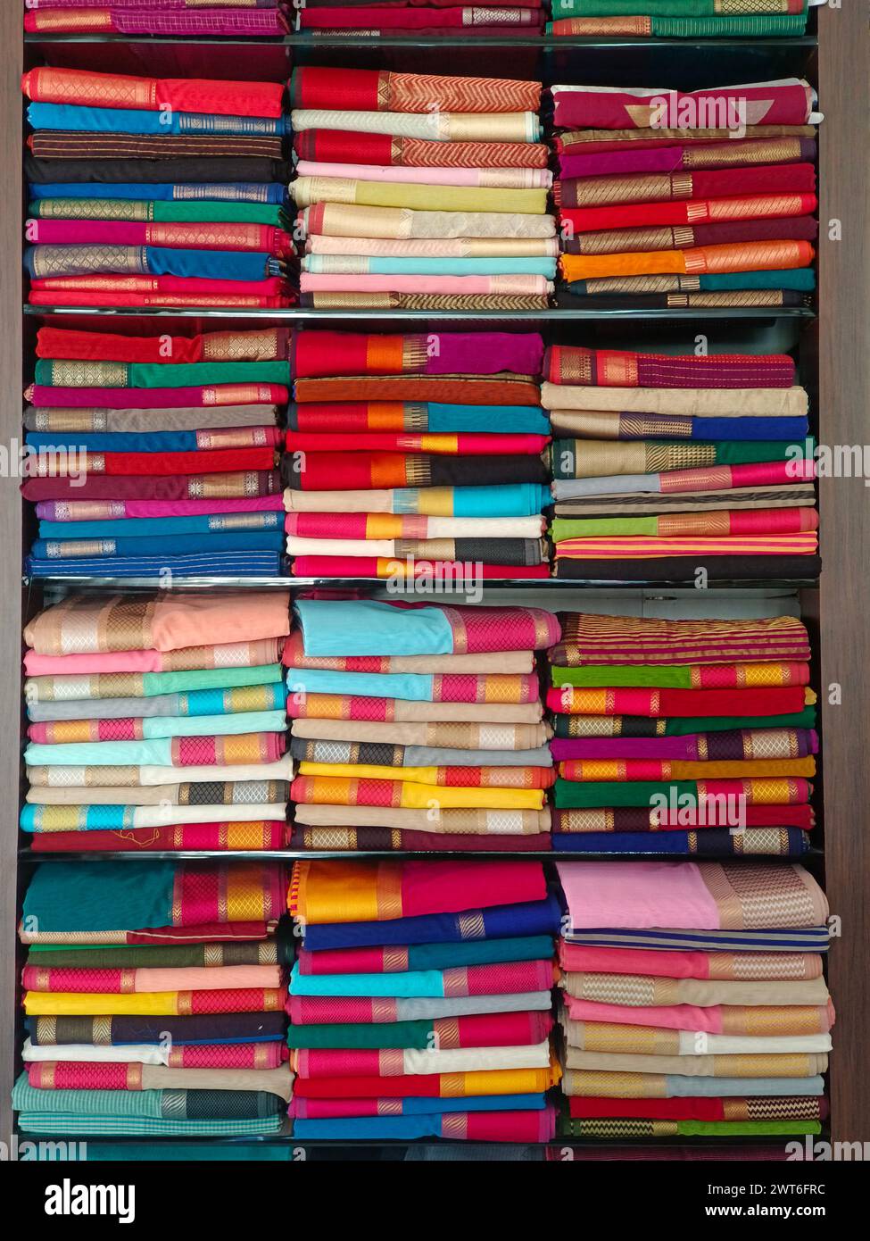 Neatly stacked colorful designer silk saris in racks in a textile shop ...