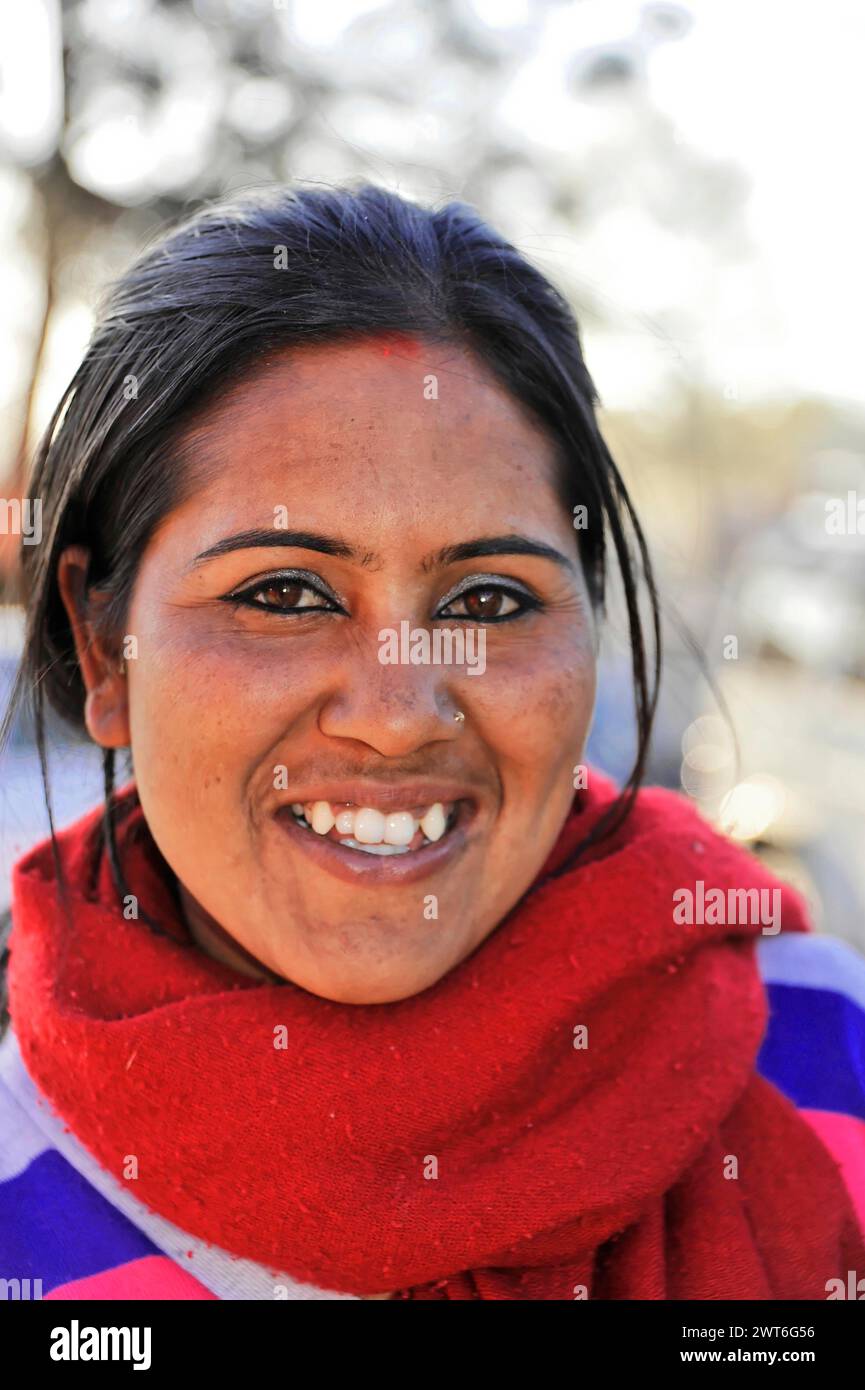A smiling woman with a red scarf in front of a blurred background ...