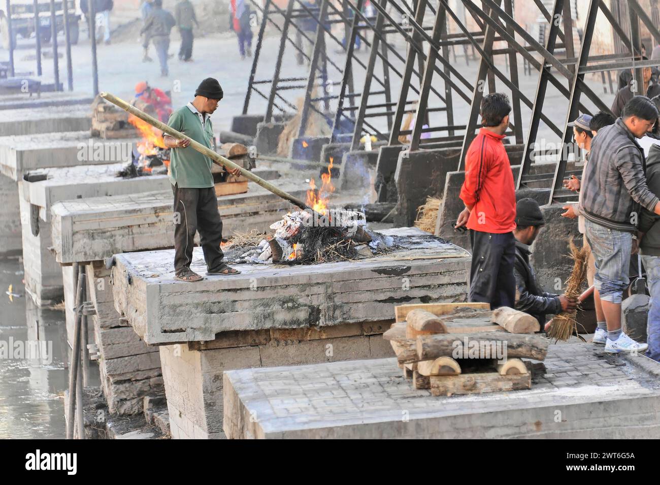 Ritual burning with people standing around a fire on concrete platforms ...