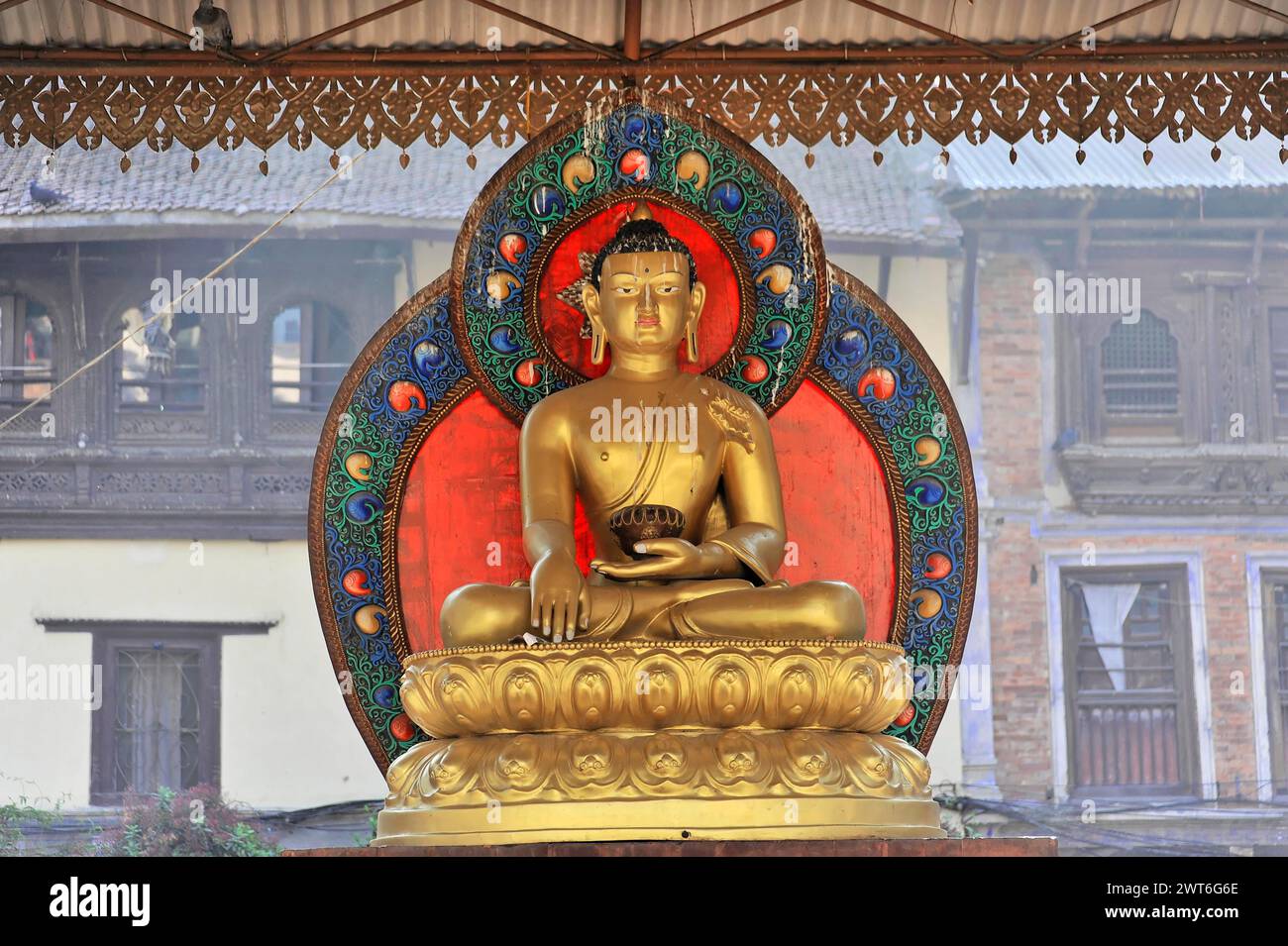 Golden Buddha statue in front of a colourful mandala in traditional ...
