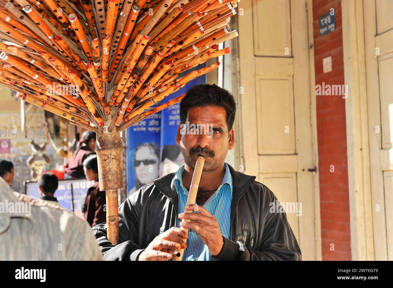 A street musician concentrates on playing a flute in an urban ...