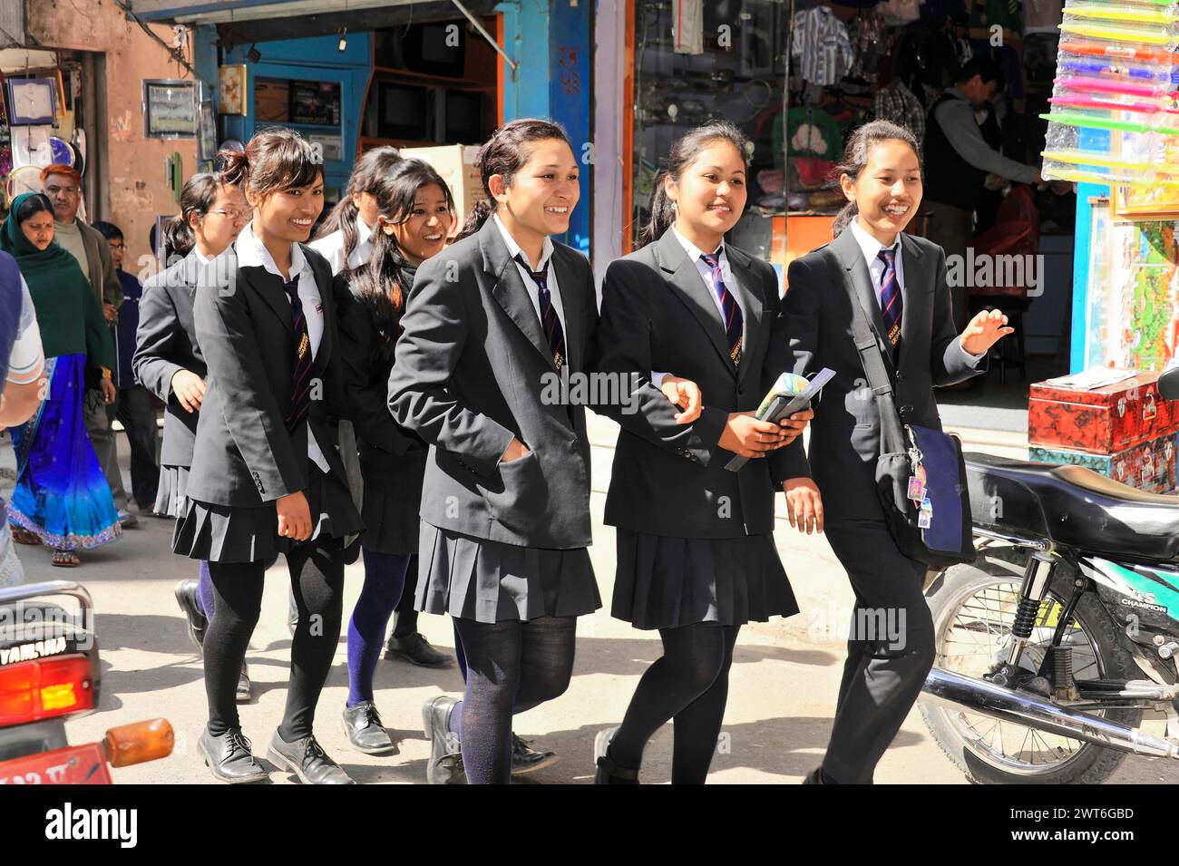 A group of young woman in school uniforms on the road, looking cheerful ...