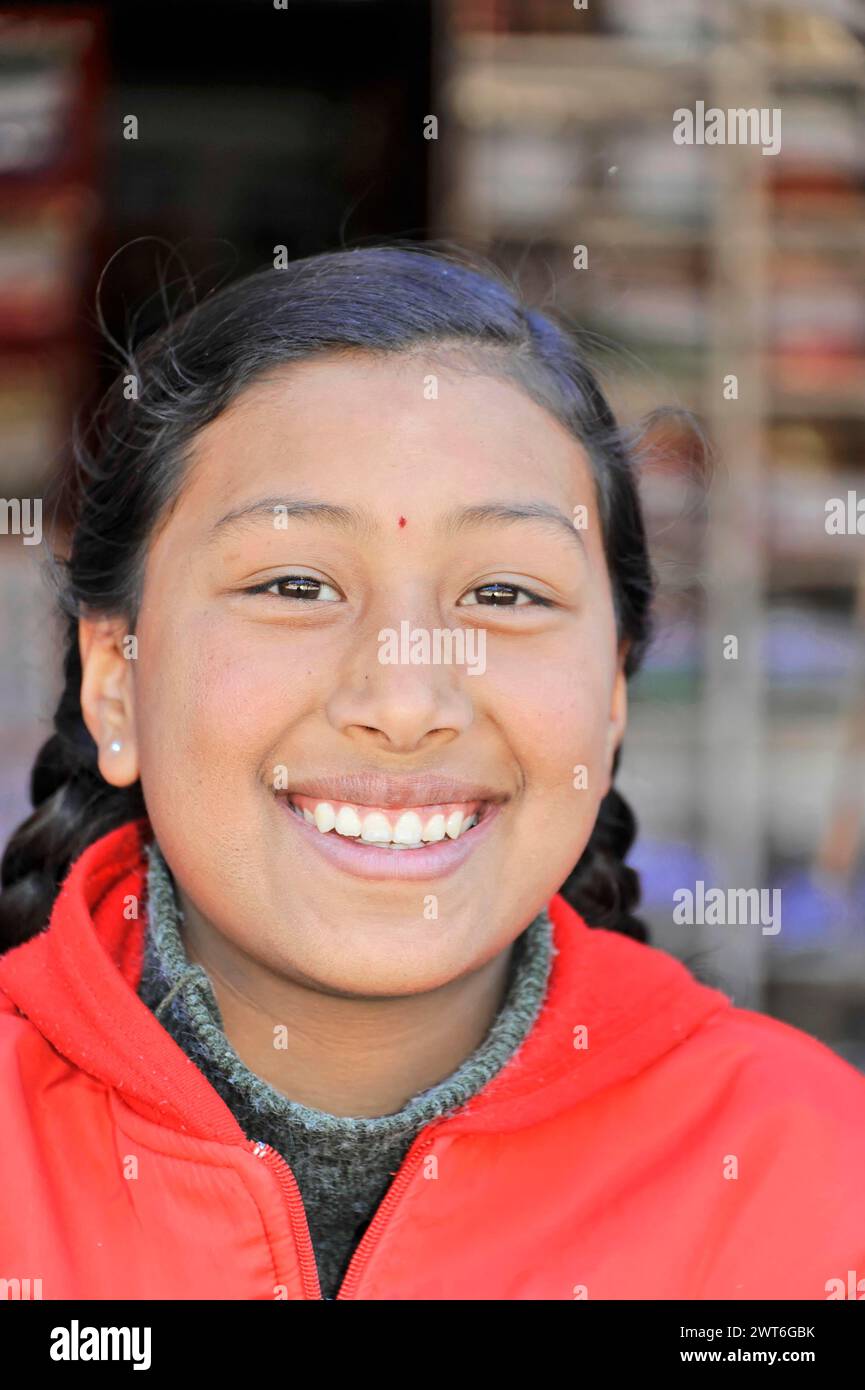 A happy young girl in a red jacket smiles at the camera, Kathmandu ...