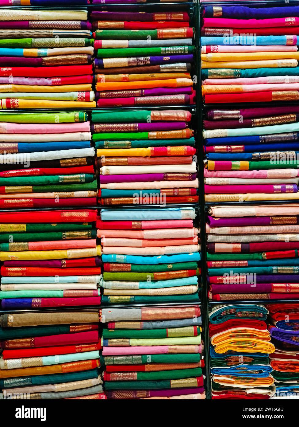 Neatly stacked colorful designer silk saris in racks in a textile shop ...