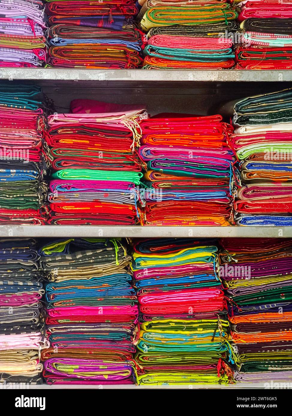 Neatly stacked colorful designer silk saris in racks in a textile shop ...