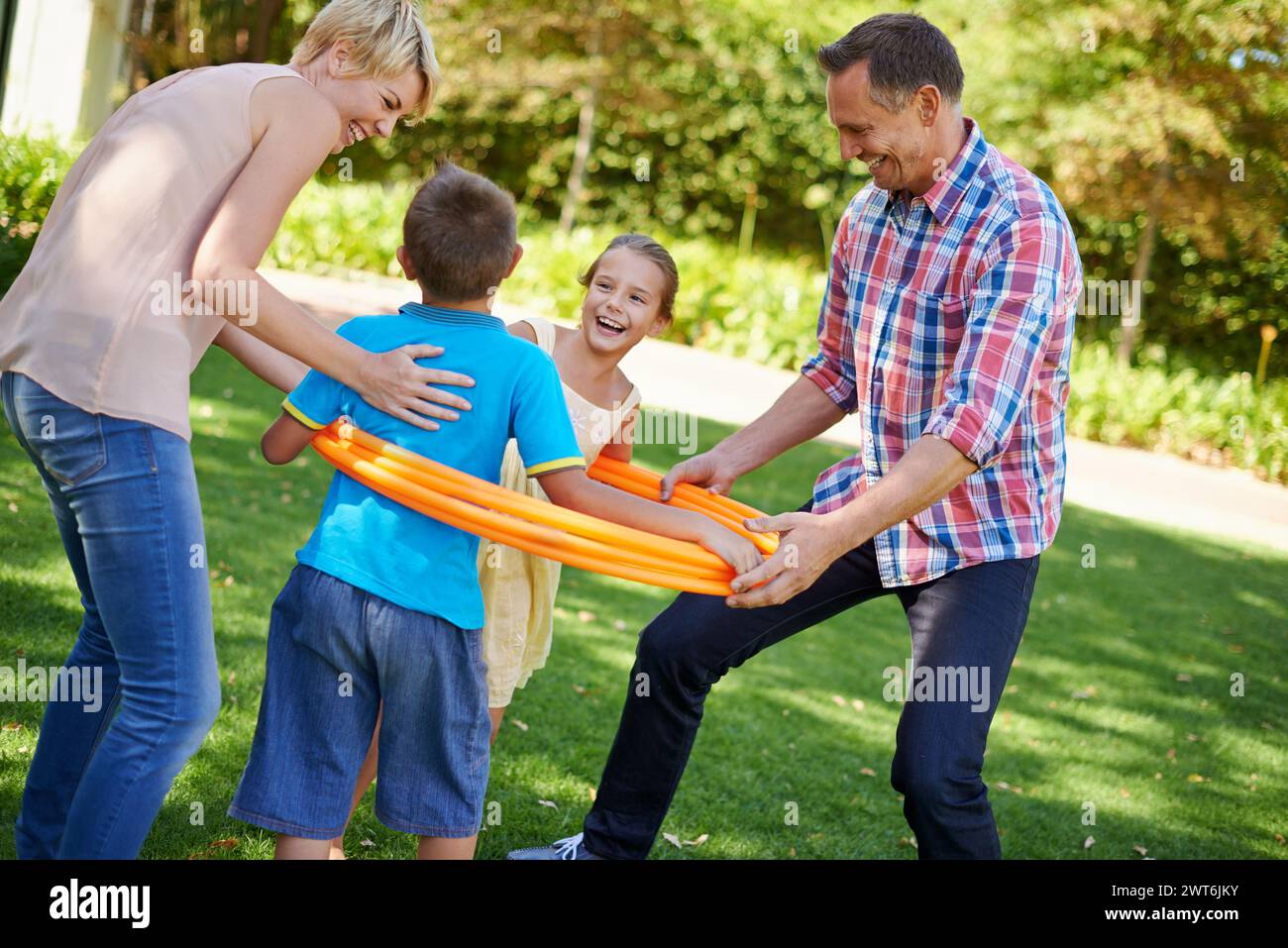 Parents, children and hula hoop in park as family, playing and bonding ...