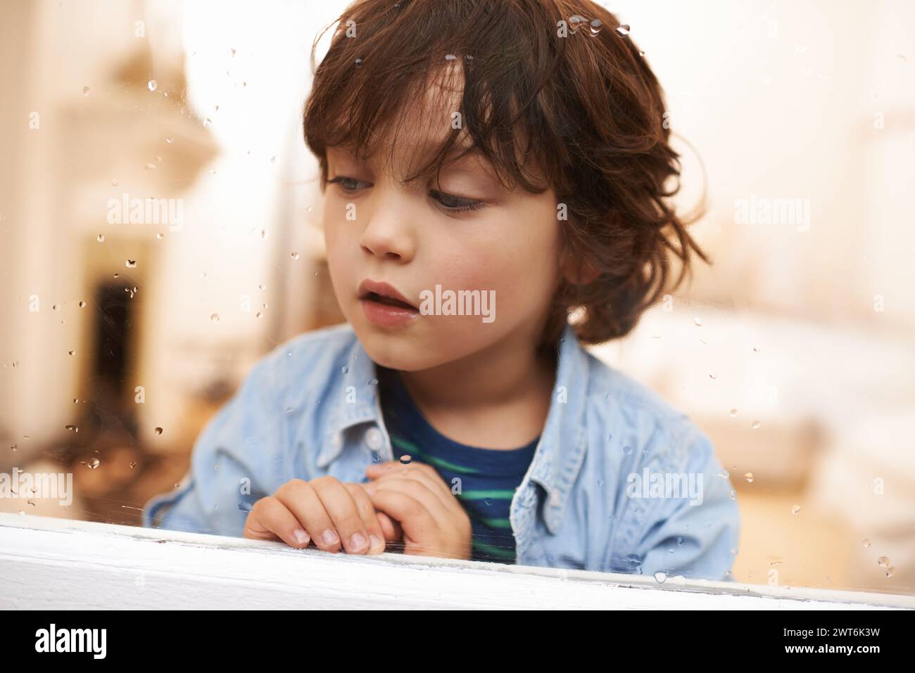 Window, sitting and boy in home for rain, bored or lonely for ...