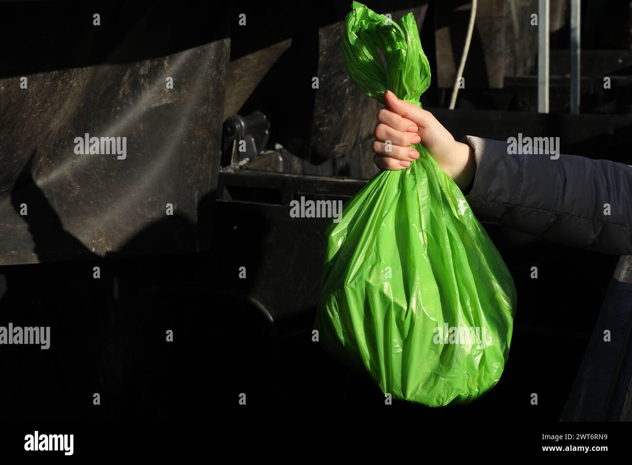 Woman throwing trash bag full of garbage in bin outdoors, closeup Stock ...